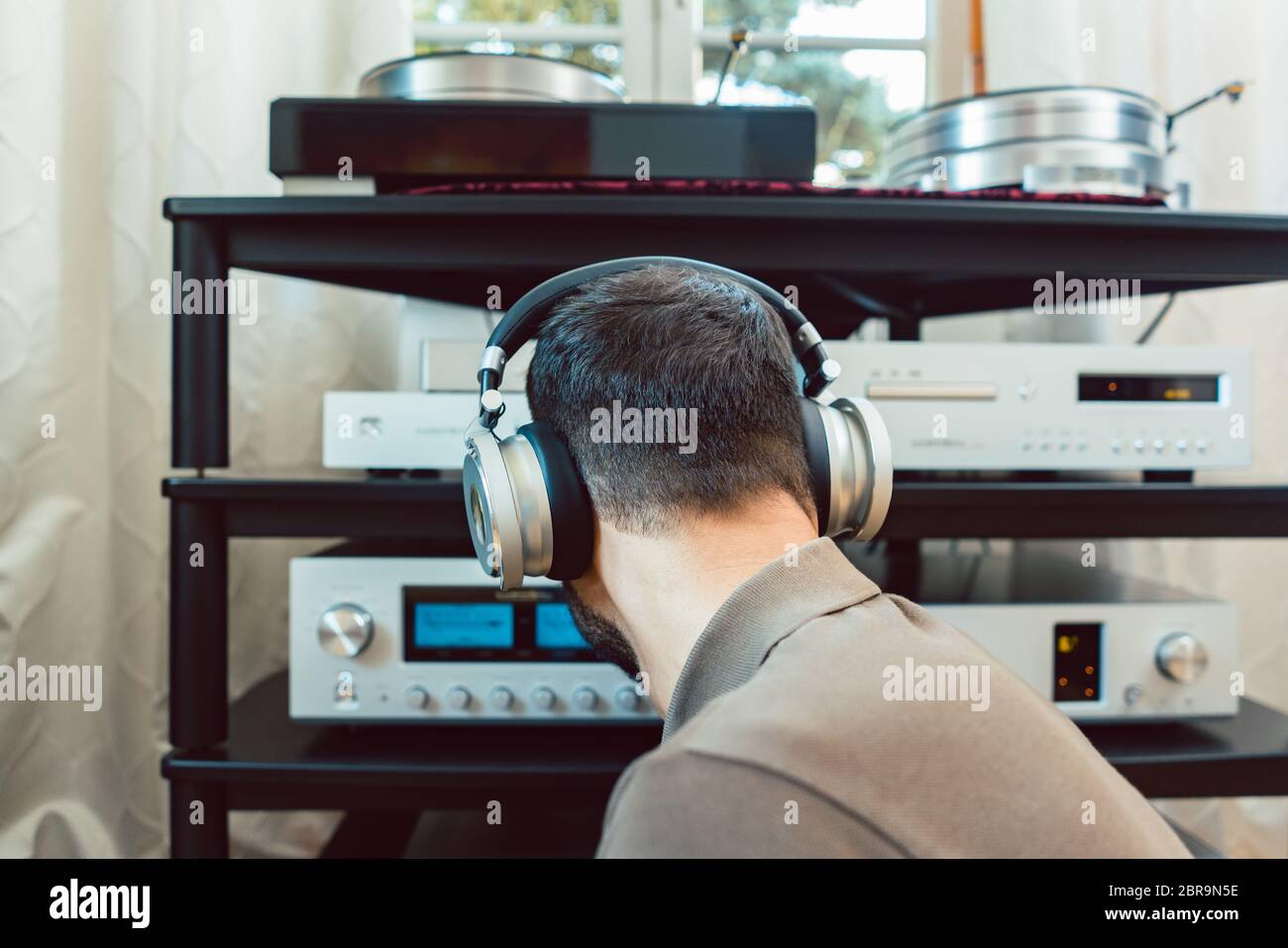 Man turning up the volume on home Hi-Fi stereo for louder music Stock ...