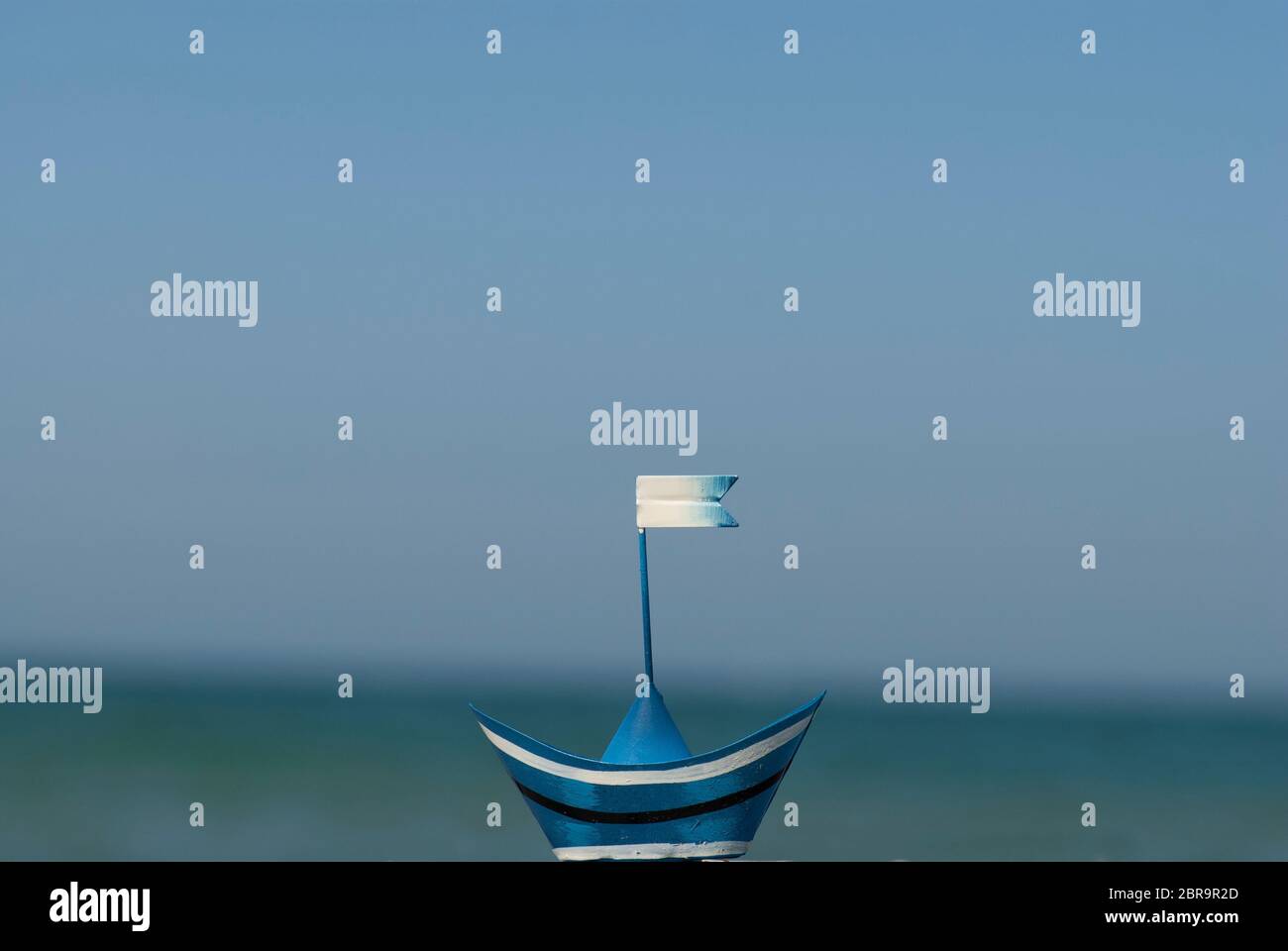 Little decorative boat with flag across blue sky and water Stock Photo ...