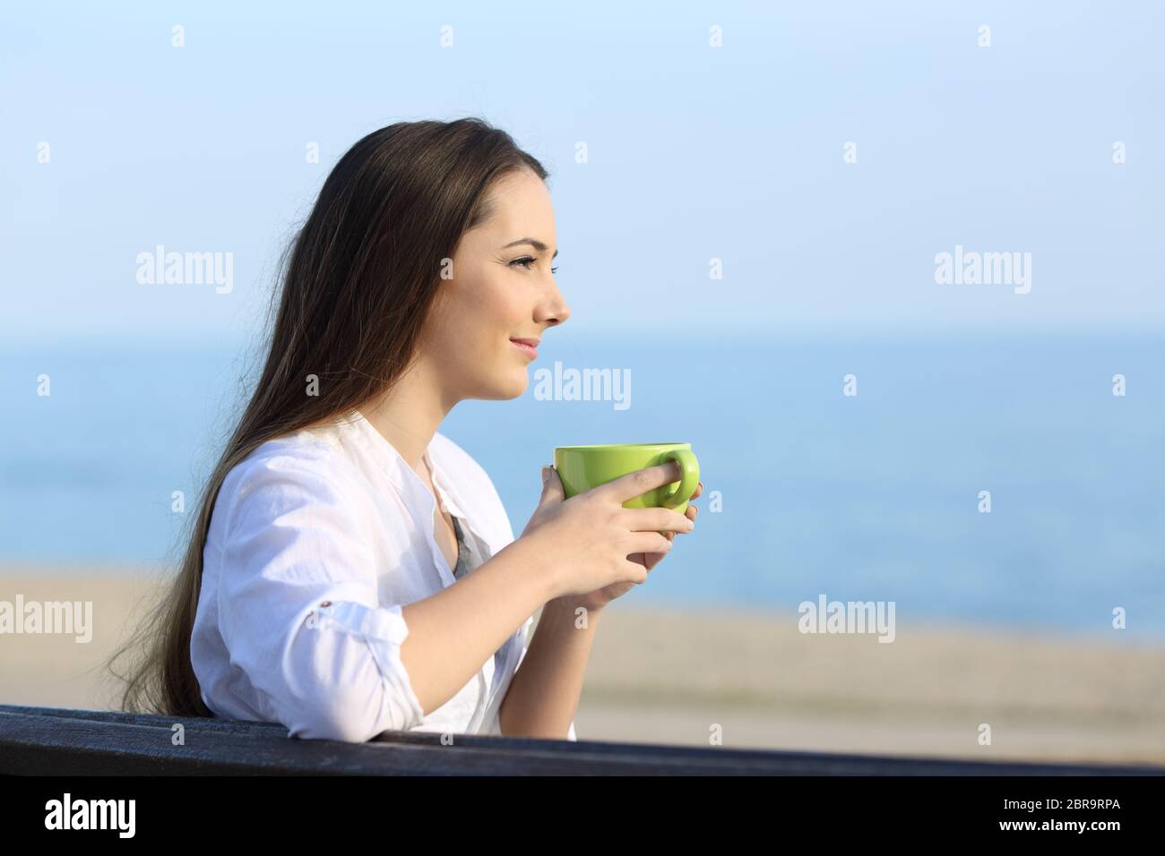 Profile of a woman relaxing drinking coffee sitting on a bench on the ...