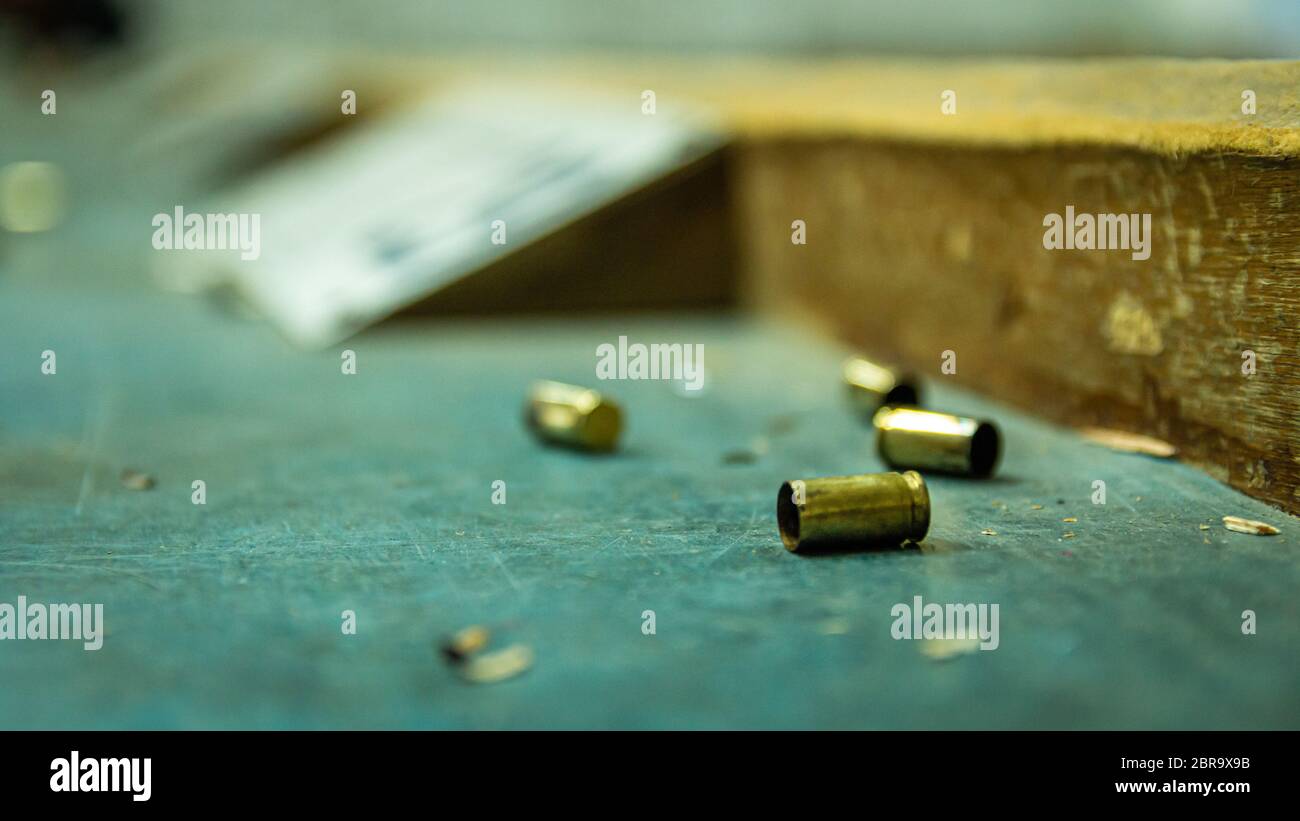 Empty pistol bullet shells on wooden table in a shooting range. Extreme ...