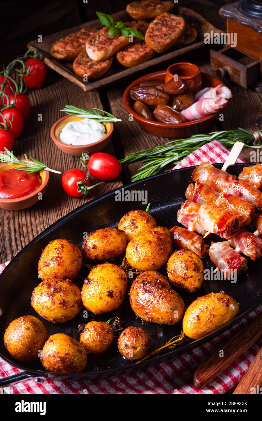 Rustic dates wrapped in bacon and young roasted potato Stock Photo - Alamy