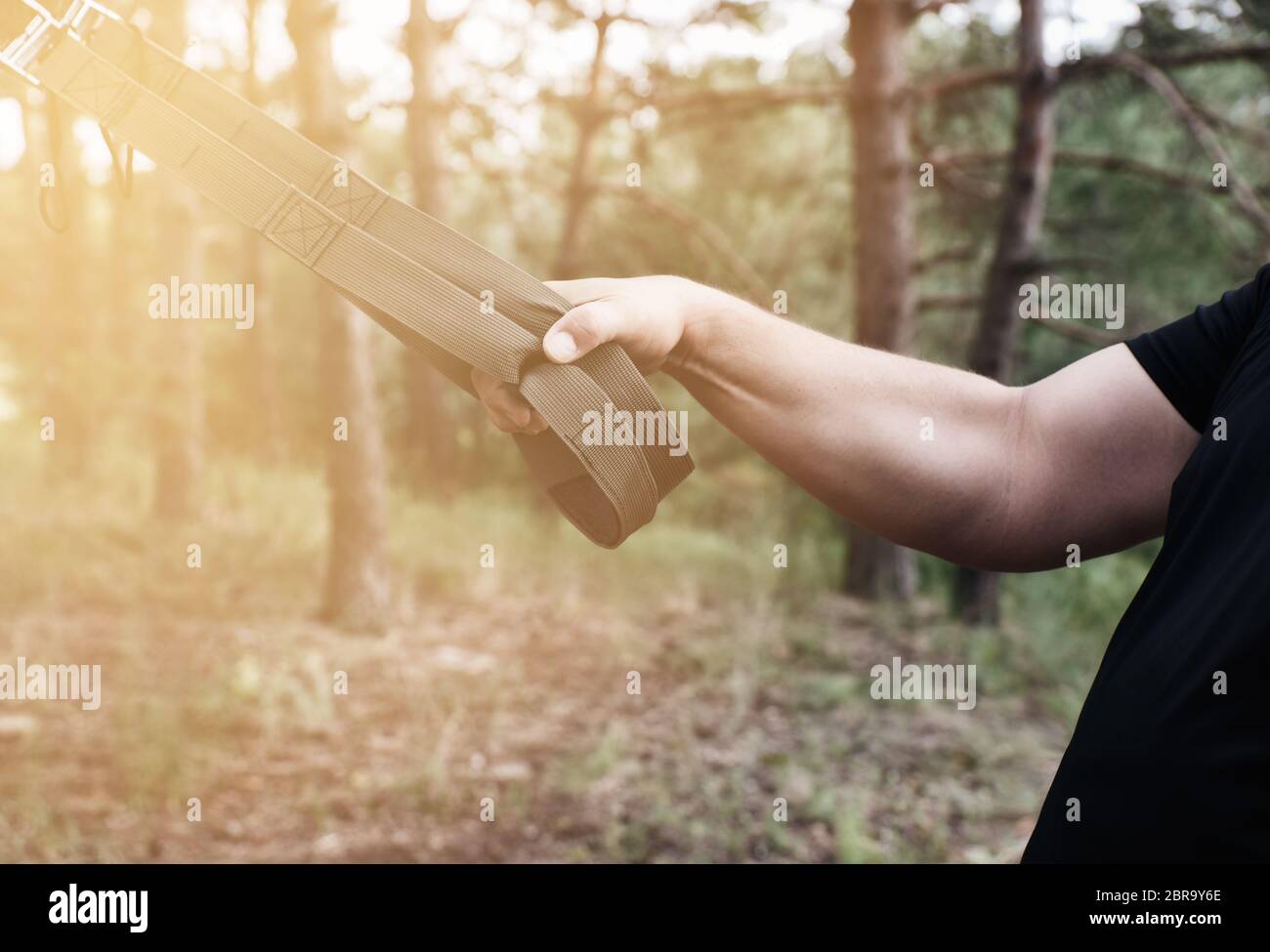 athlete in black uniform does strength exercises with a tethered rope ...