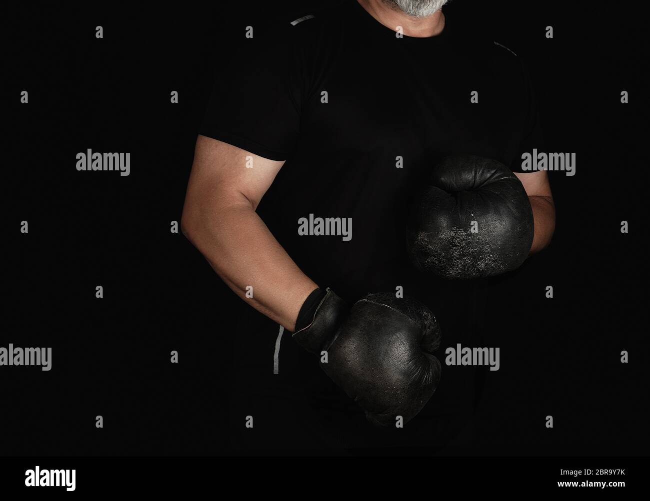 young man stands in a boxing rack, wearing very old vintage black ...