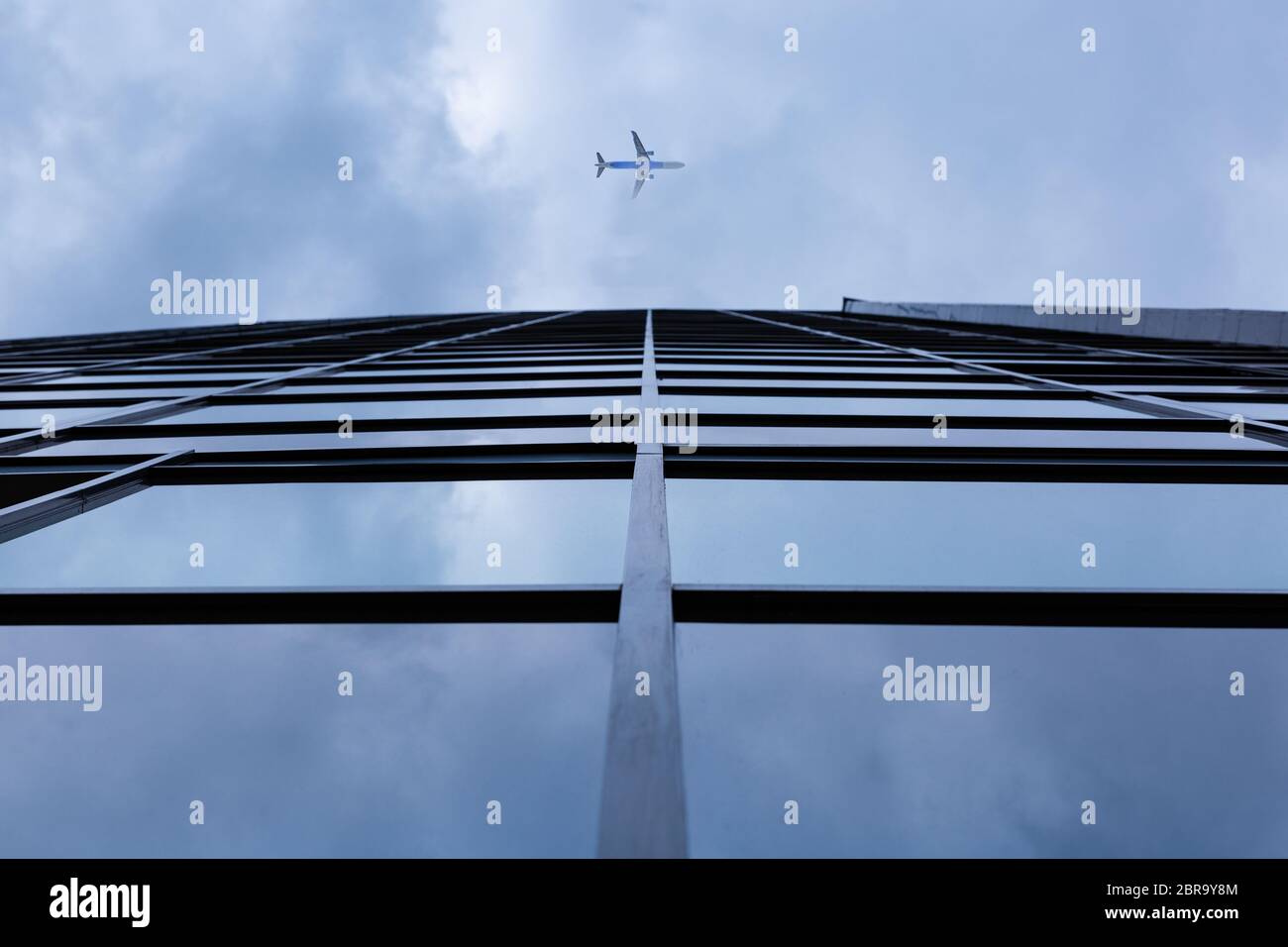 Airplane flying above modern architecture glass office building Stock ...
