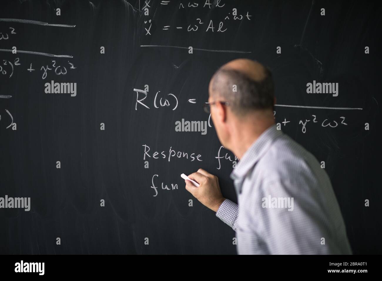 Math teacher drawing fuction graph on a blackboard during mathclass ...