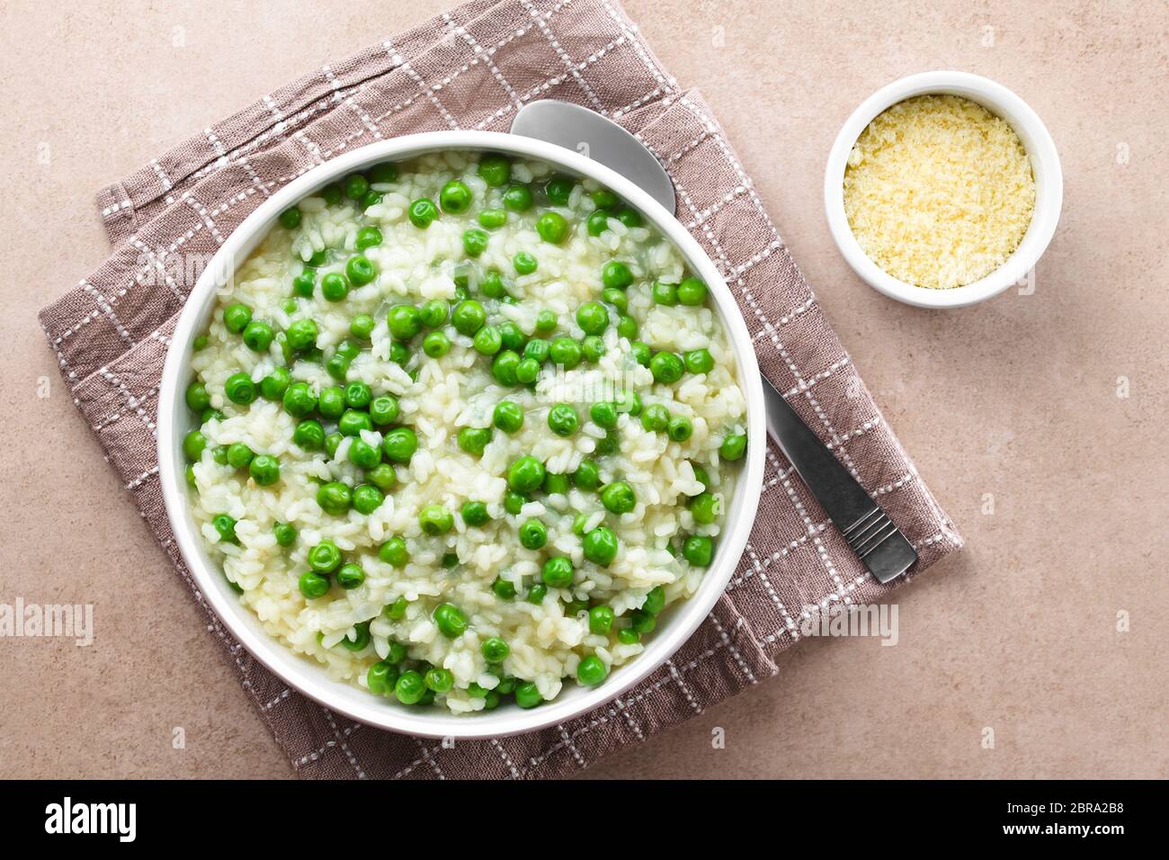 Fresh homemade creamy green pea risotto in bowl, spoon and grated ...