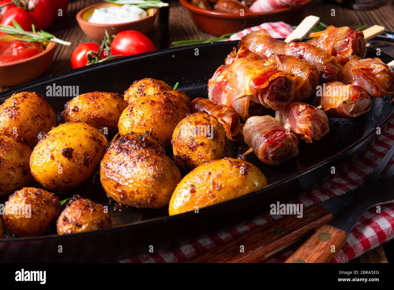 Rustic dates wrapped in bacon and young roasted potato Stock Photo - Alamy