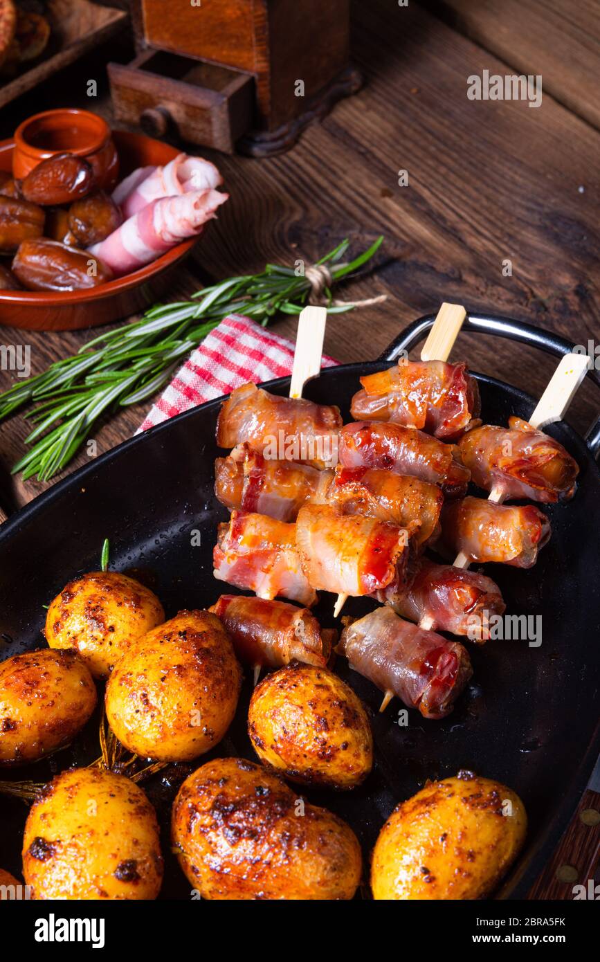 Rustic dates wrapped in bacon and young roasted potato Stock Photo - Alamy