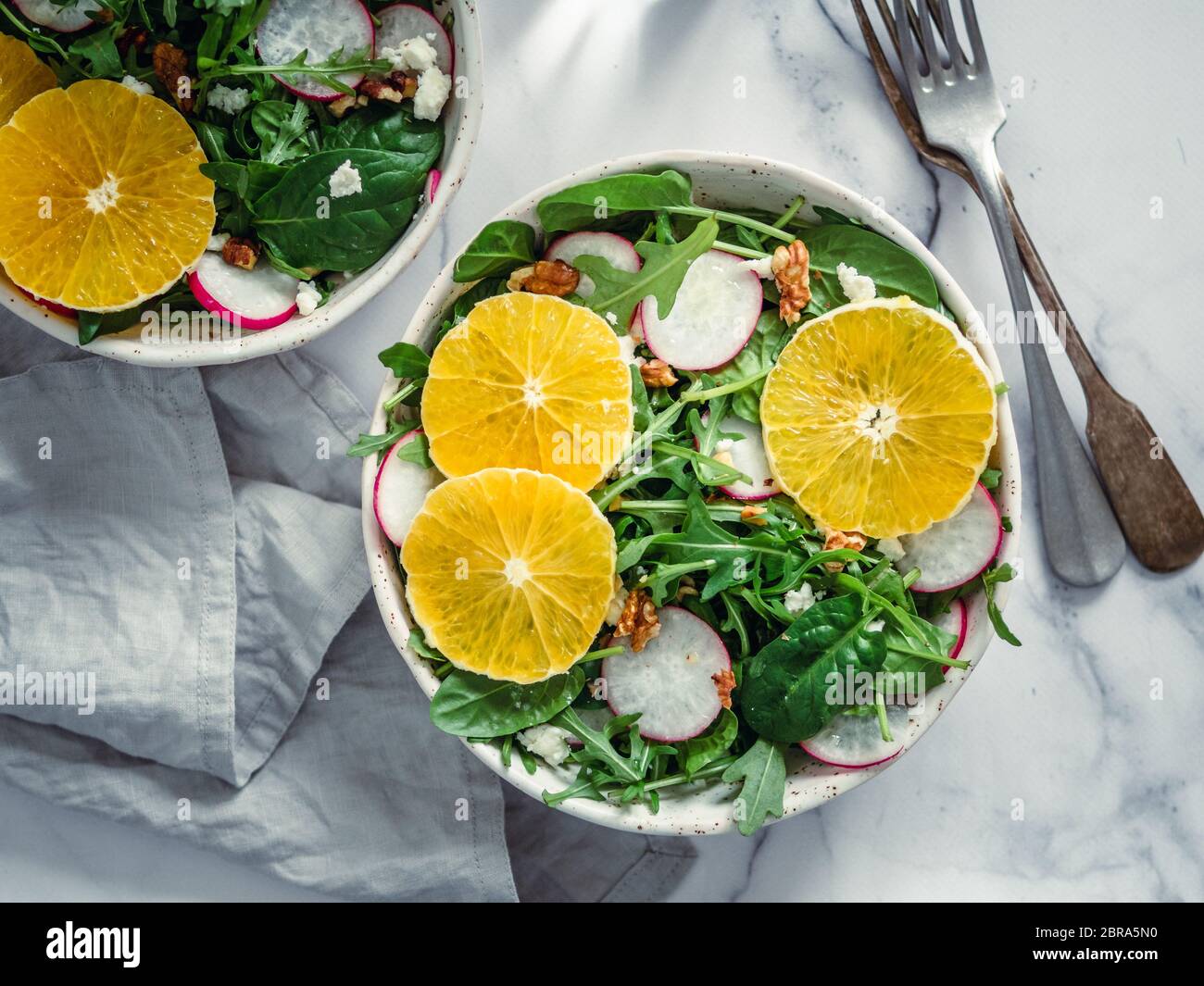 Vegan salad bowl with oranges, spinach, arugula, radish, nut. Top view ...