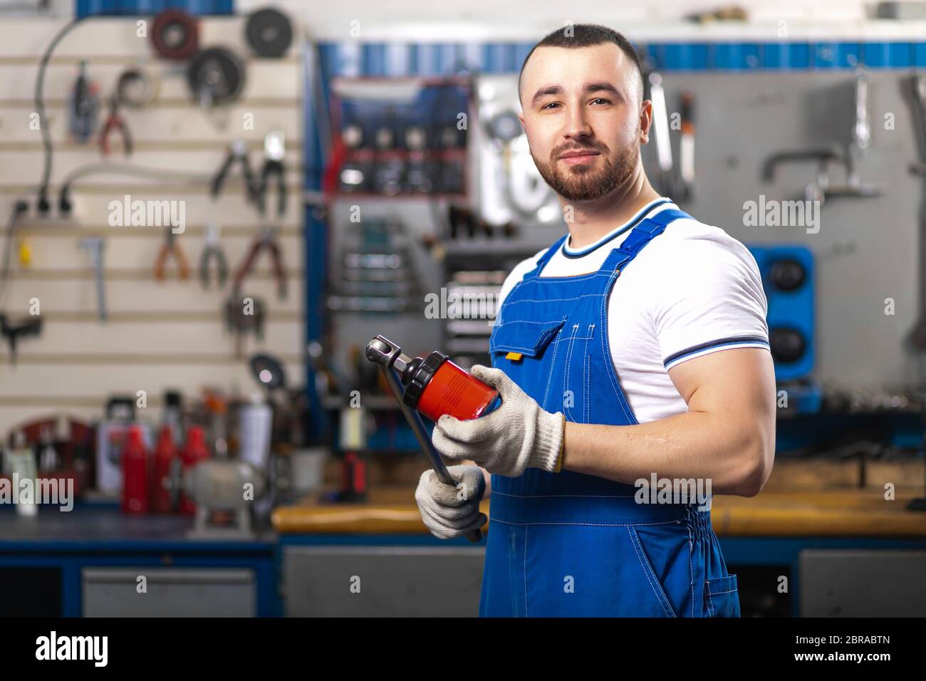 Handsome young male auto mechanic in special uniform clothes is ...