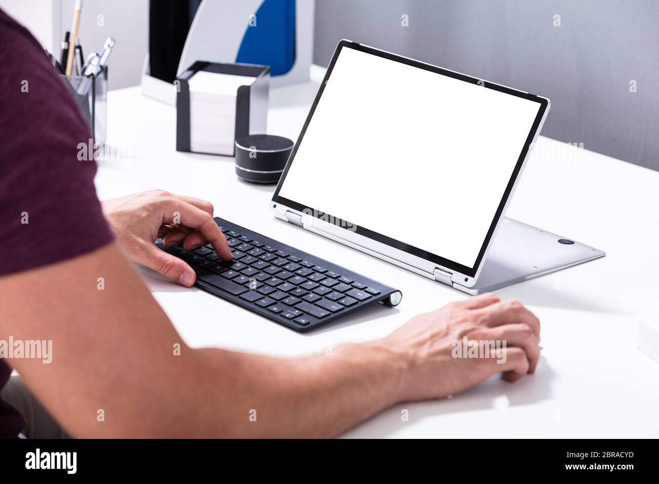 Close-up of a businessman's hand using laptop with blank white screen ...