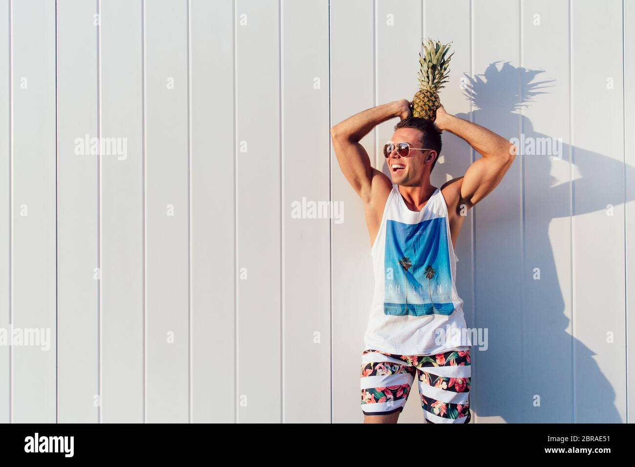 Outdoor photo of cheerful muscular man in sunglasses holding a ...