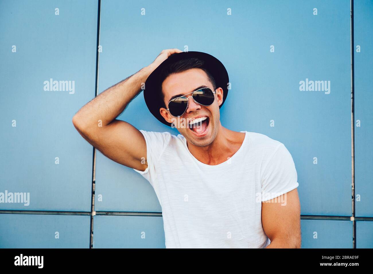 Portrait of a cheerful muscle guy in sunglasses and hat looking at ...