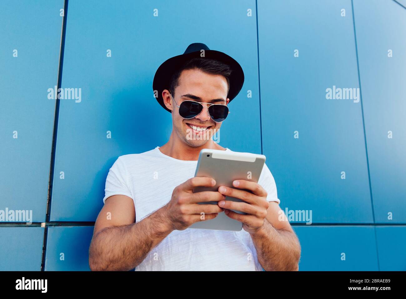 Cool cheerful man watching something on computer tablet, standing ...