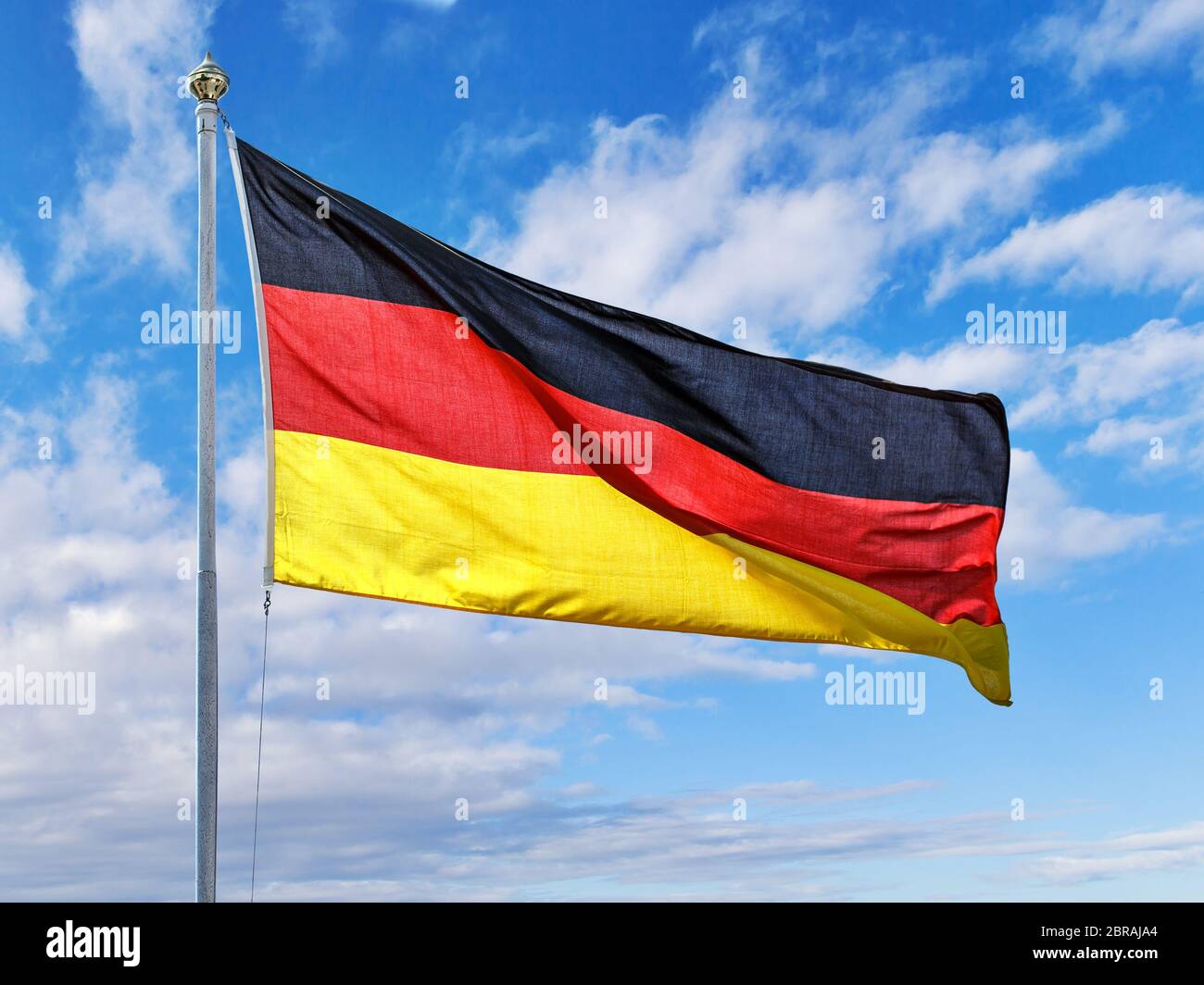 The national flags of Germany on the background of blue sky with clouds ...