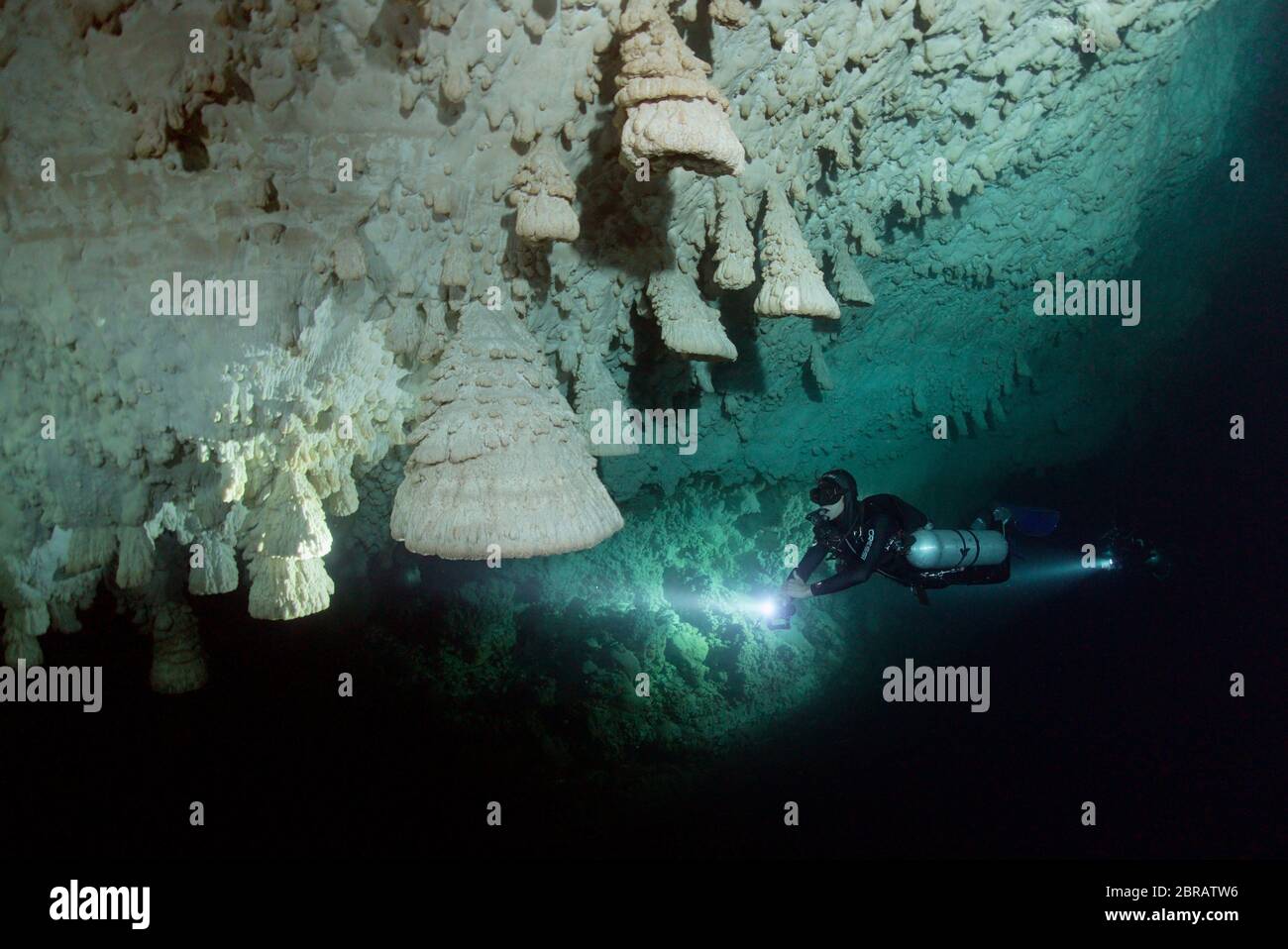 Technical sidemount diver swims along the wall of Cenote Zapote ...