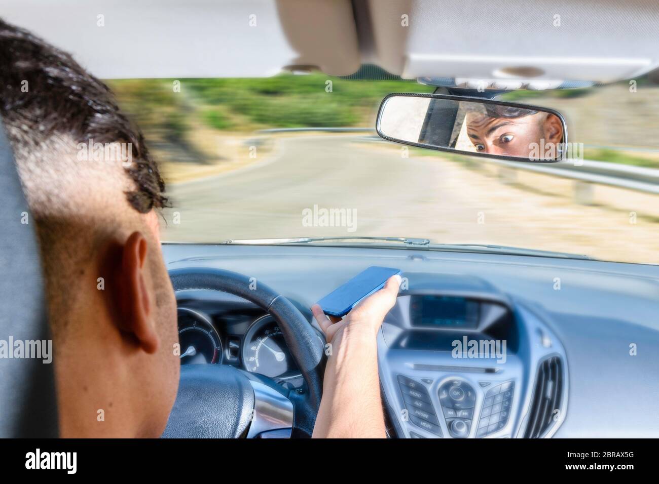Young driver, using smartphone, on the road in the car. Distraction and ...