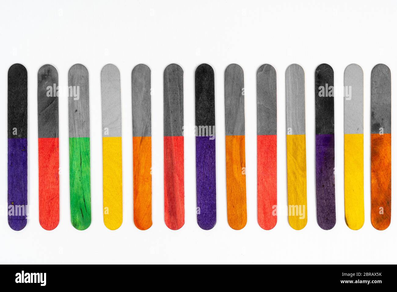 row of half colored and half monochrome wooden slats on a white surface ...