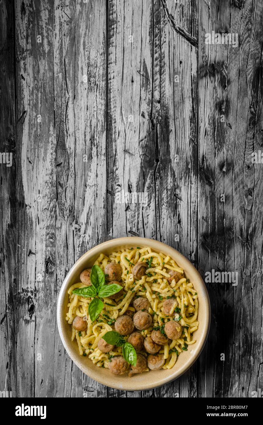 Homemade spaetzle, barbecue sausage and fresh cheese, herbs on rustic ...