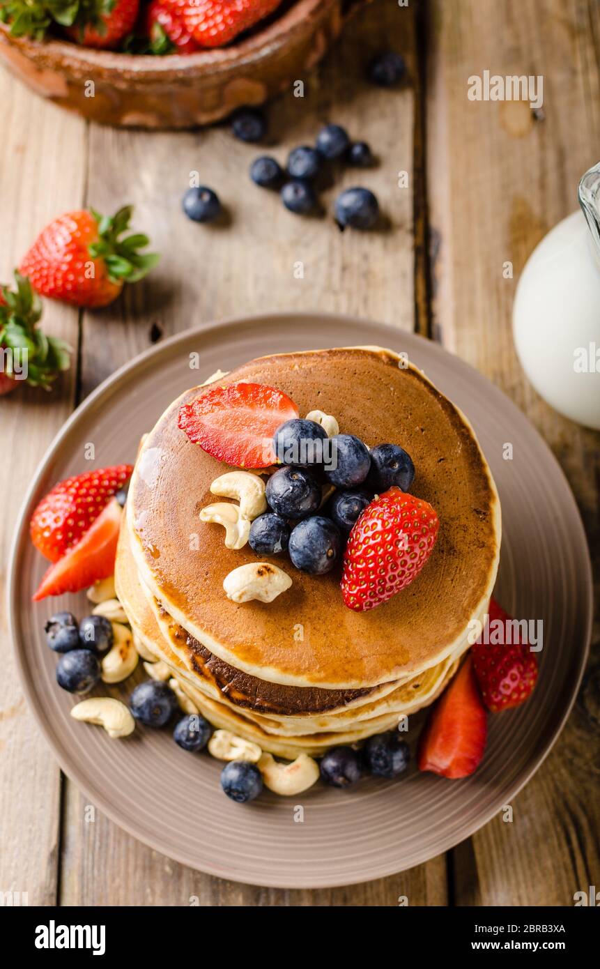 Original american pancakes with berries, roasted nuts and milk behind ...
