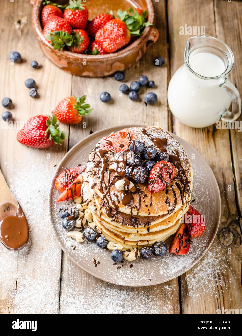 Original american pancakes with berries, roasted nuts and milk behind ...
