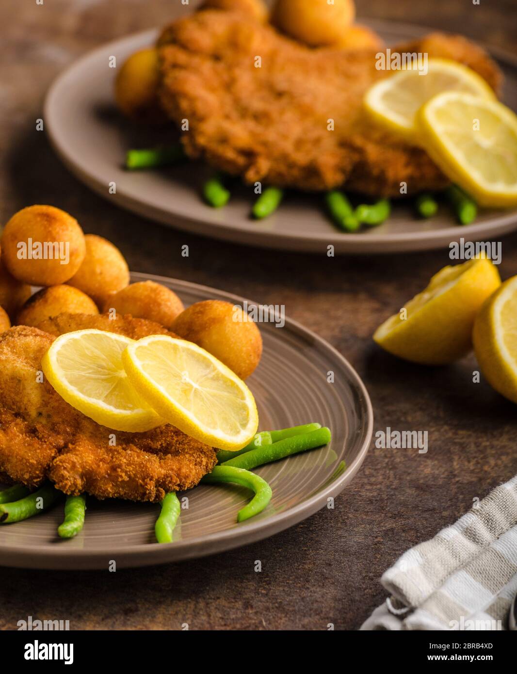 Wiener schnitzel with potato croquettes and beans, lemon freshened ...