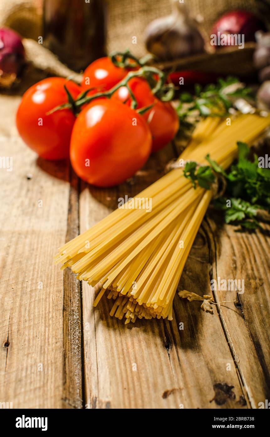 Spaghetti product photo, on wood table with tomatoes and herbs and ...
