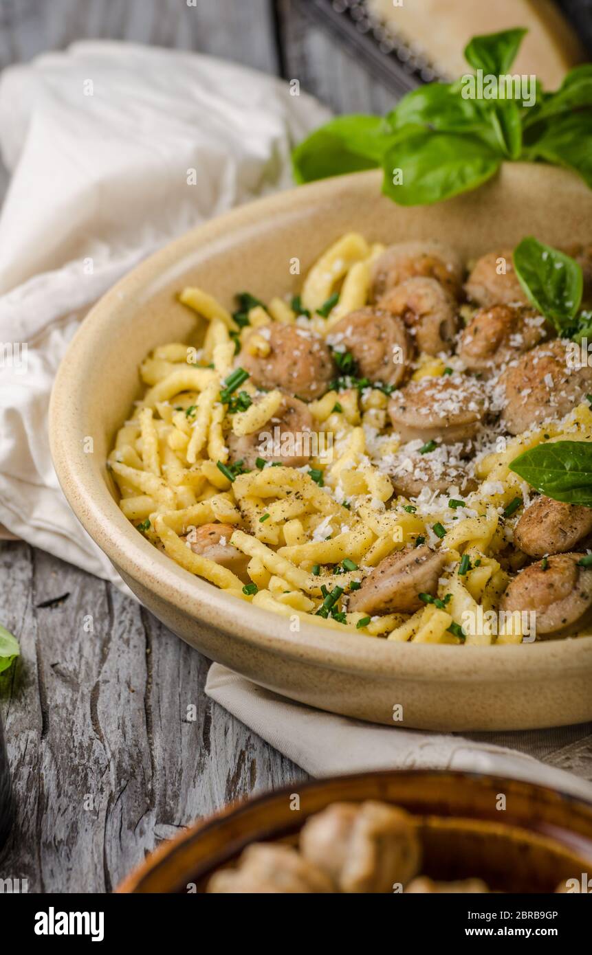 Homemade spaetzle, barbecue sausage and fresh cheese, herbs on rustic ...