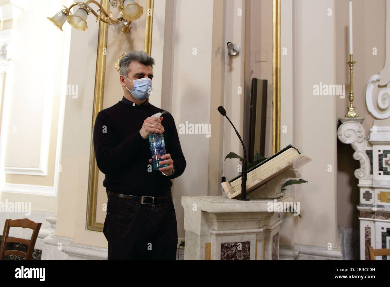 The parish priest Enzo sanitizes the microphone used for readings to ...