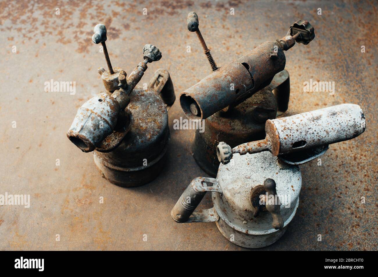 Old rusty gas blowtorch stands on a rusty sheet of iron. Scrap metal ...