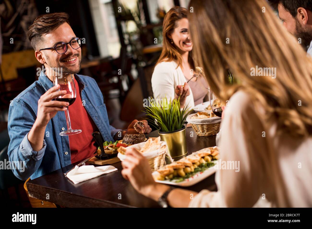 Group of happy young people having dinner in the restaurant Stock Photo ...