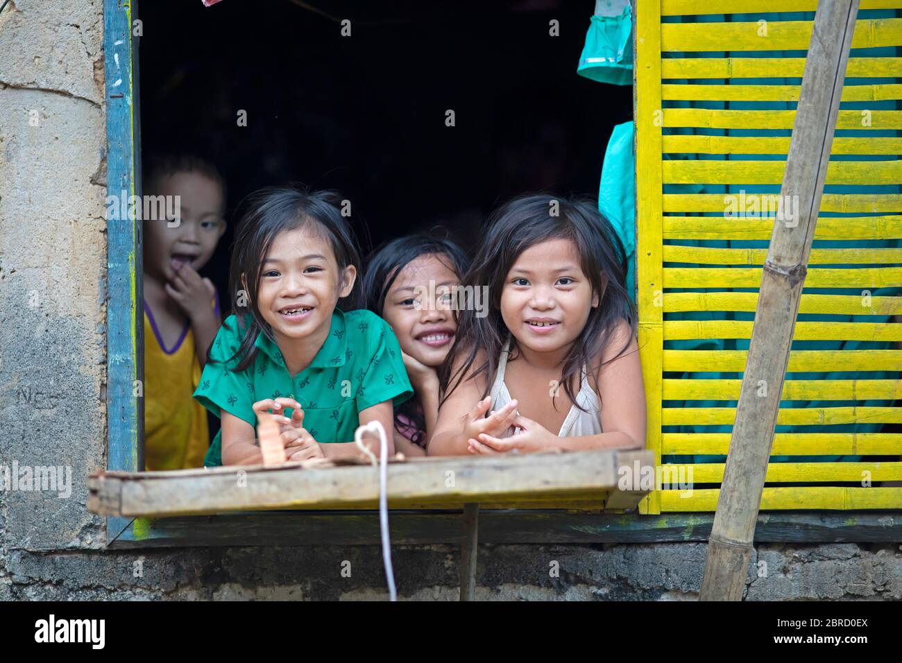 Happy children looking out of the window of their house, Anda, Bohol ...