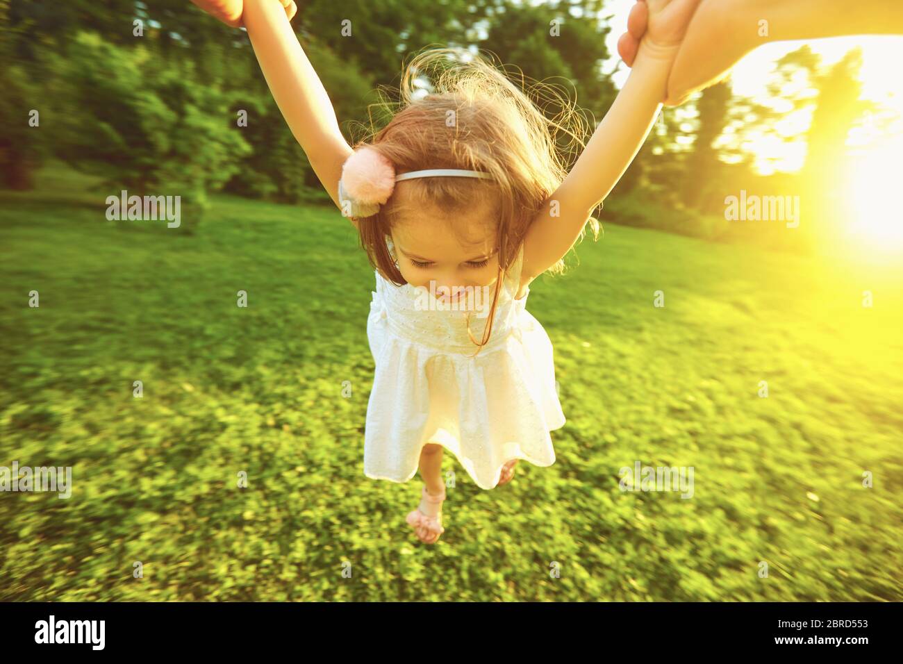 Happy child is twisted by hands in the park. Children Protection Day ...