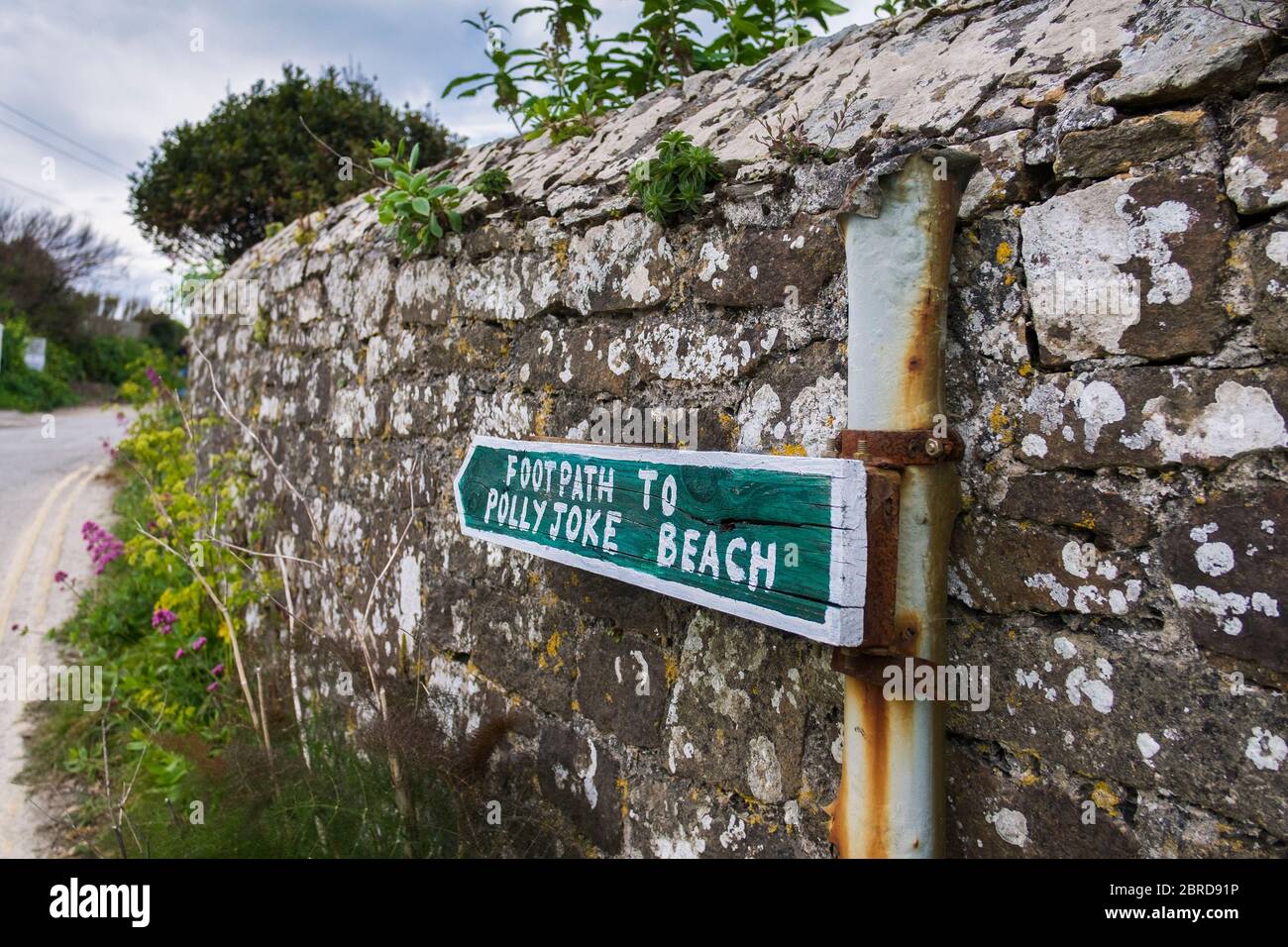 A hand painted wooden sign giving direction to Polly Joke Beach near ...