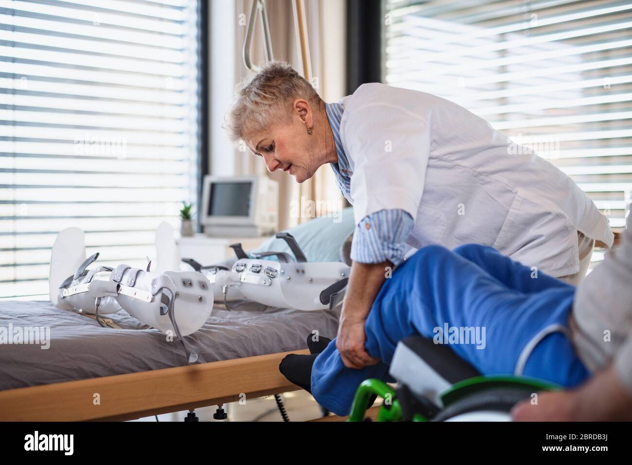 A healthcare worker and paralysed senior patient in hospital Stock ...