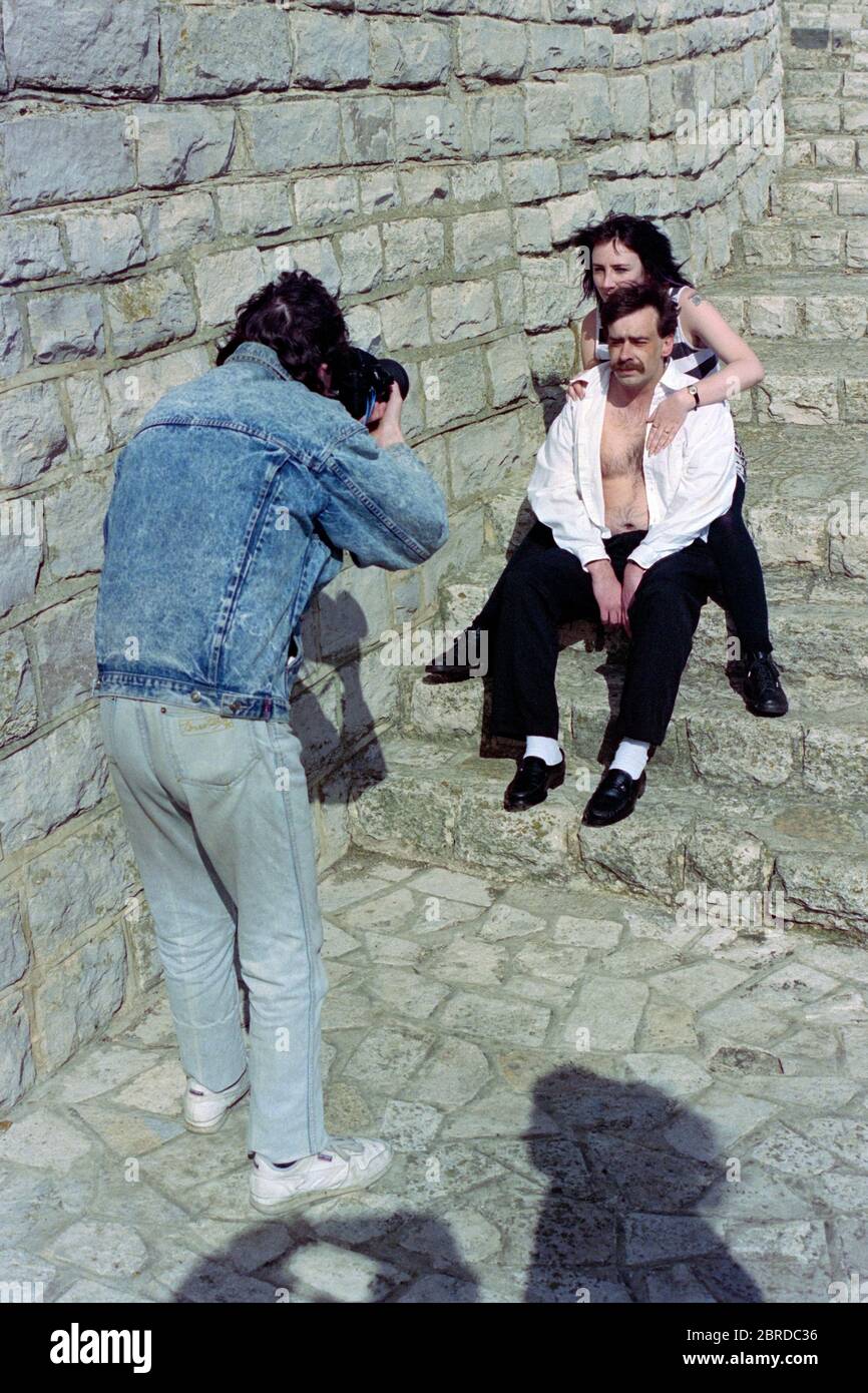 young male photographer photographing two models at a photo shoot in ...