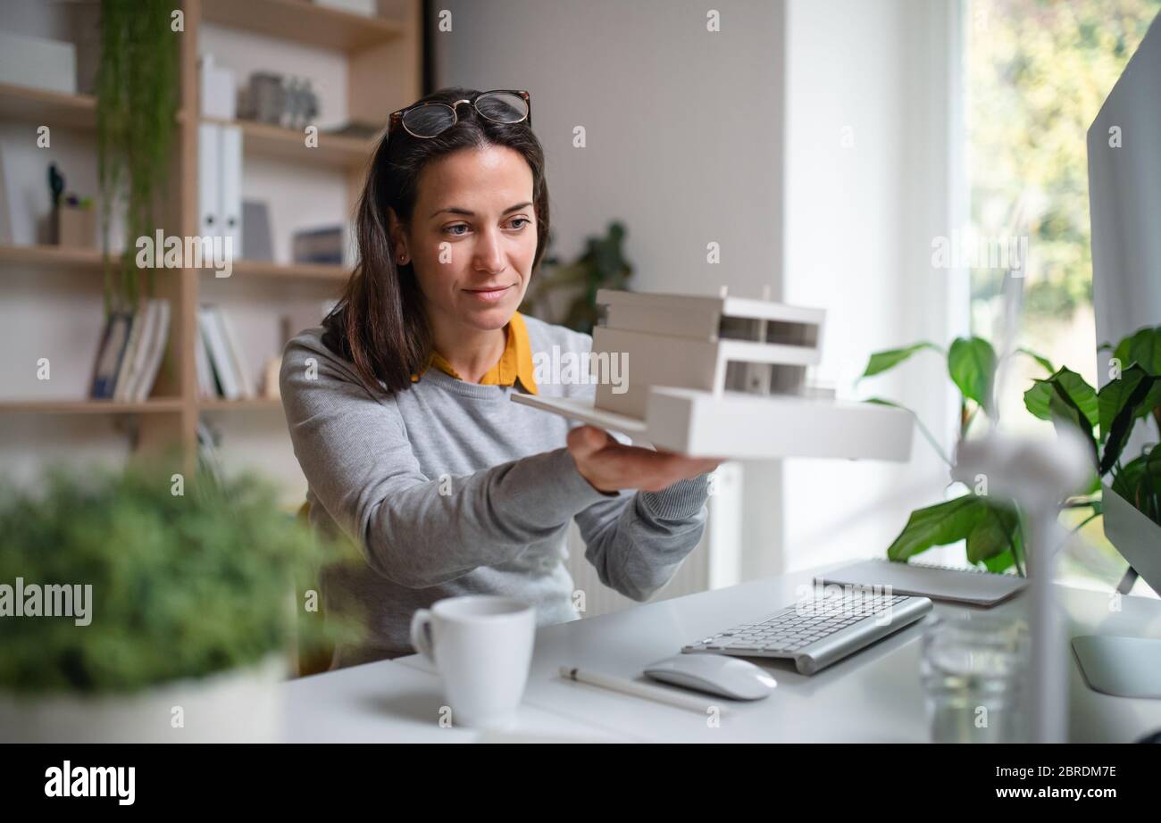 Architect with model of a house sitting at the desk indoors in office ...