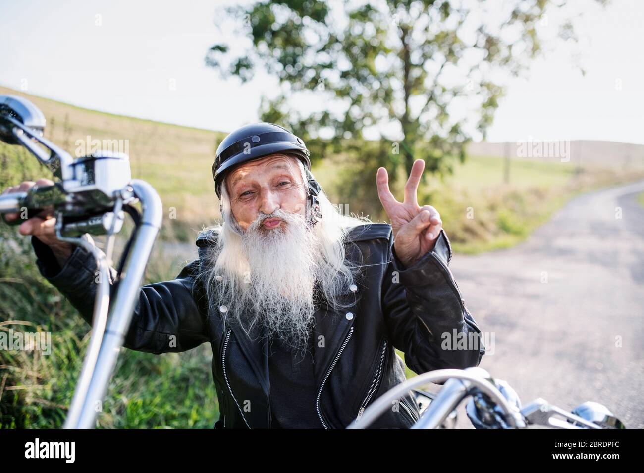 A senior man traveller with motorbike in countryside Stock Photo - Alamy