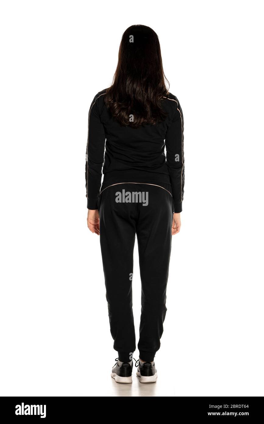 Back view of young woman in black track suit posing on white background ...