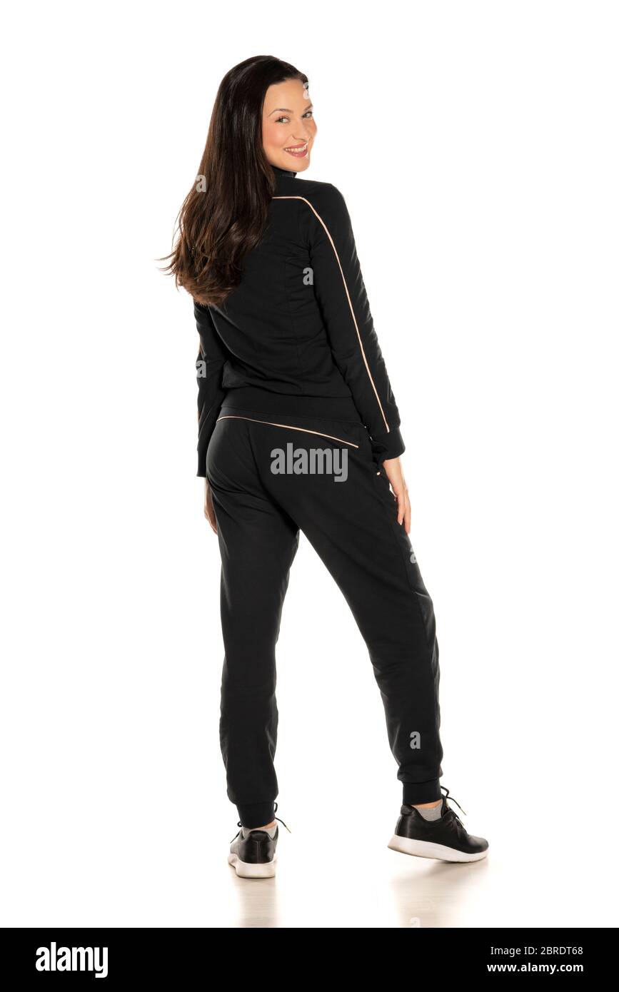 Back view of young woman in black track suit posing on white background ...