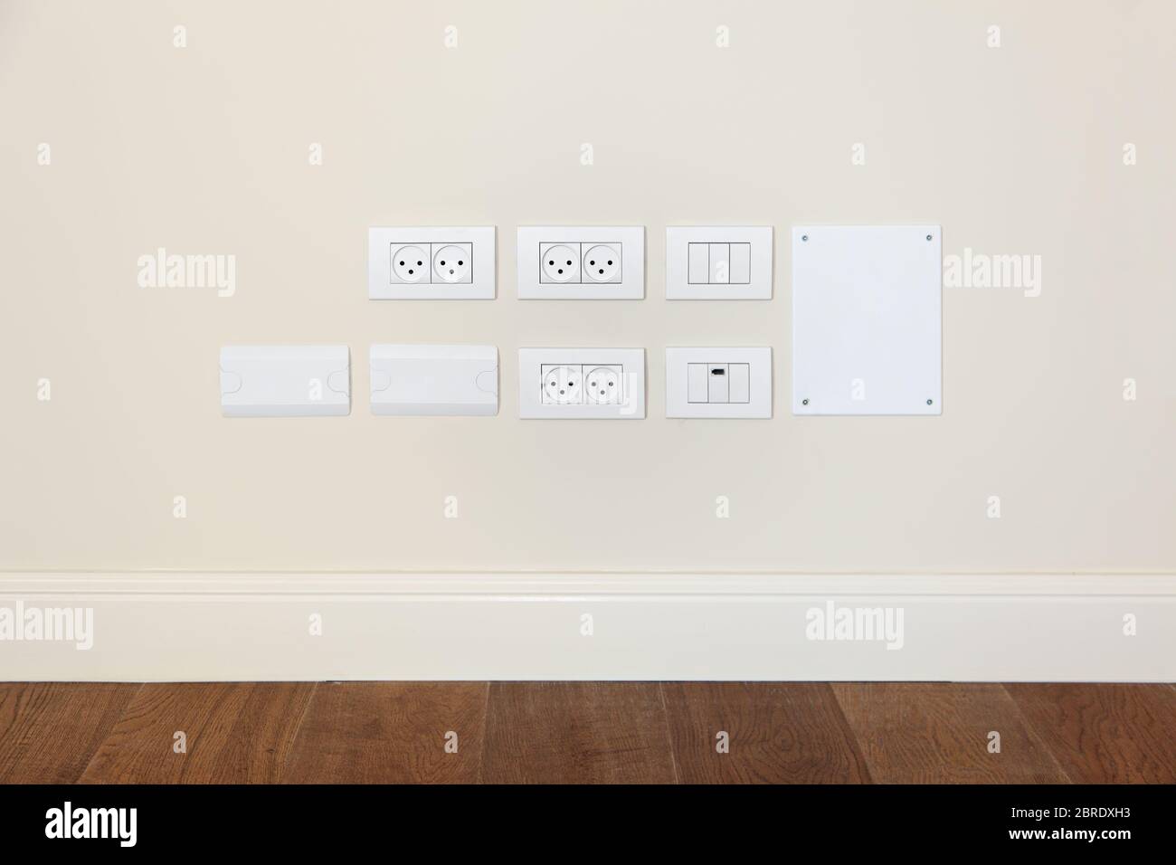 Empty wall with wooden floor. On the wall power outlet and light switch ...