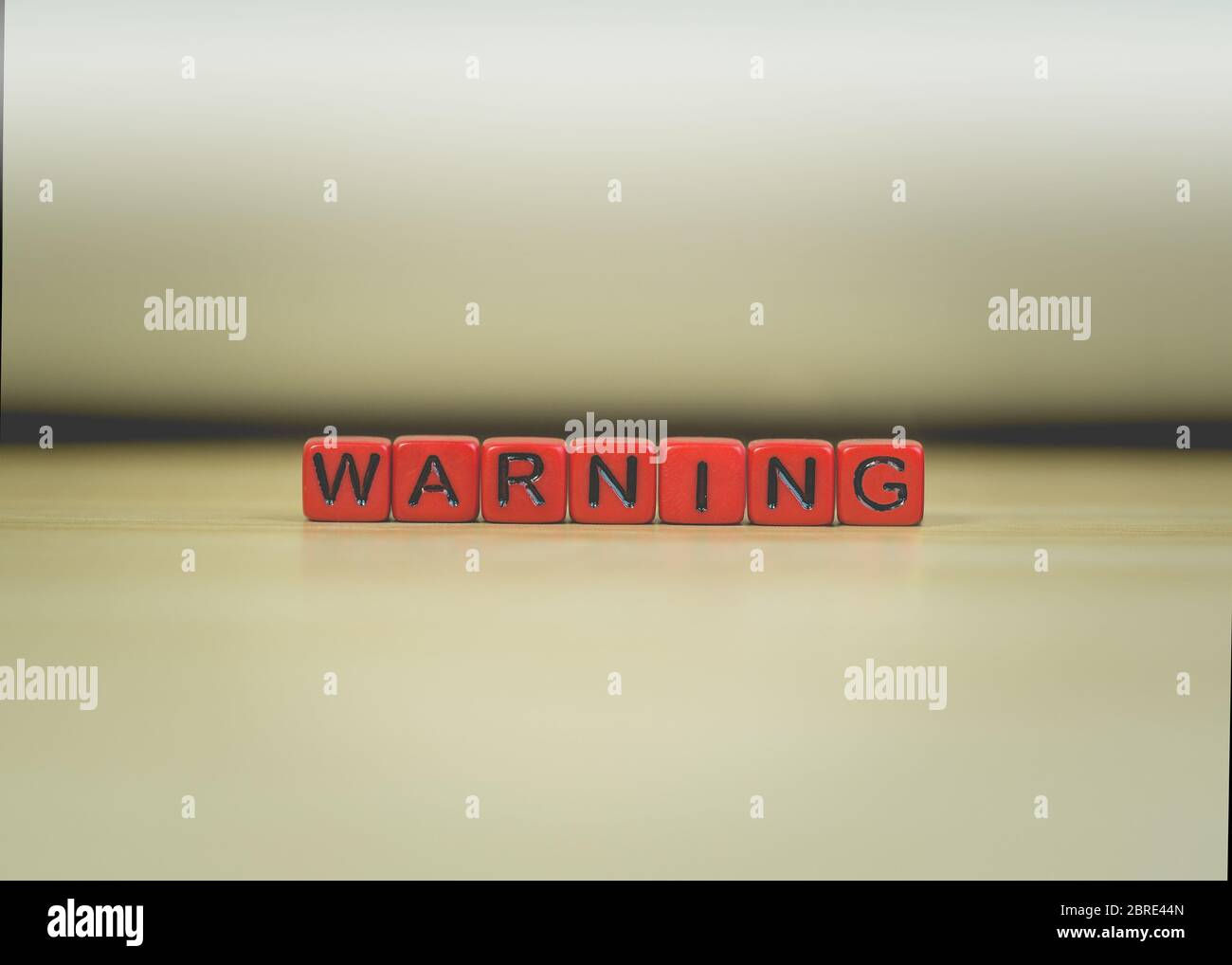 WARNING word written in cube on wooden floor on white background ...