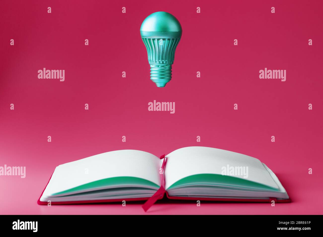 The light bulb hovers over the open pages of an empty notebook on a ...
