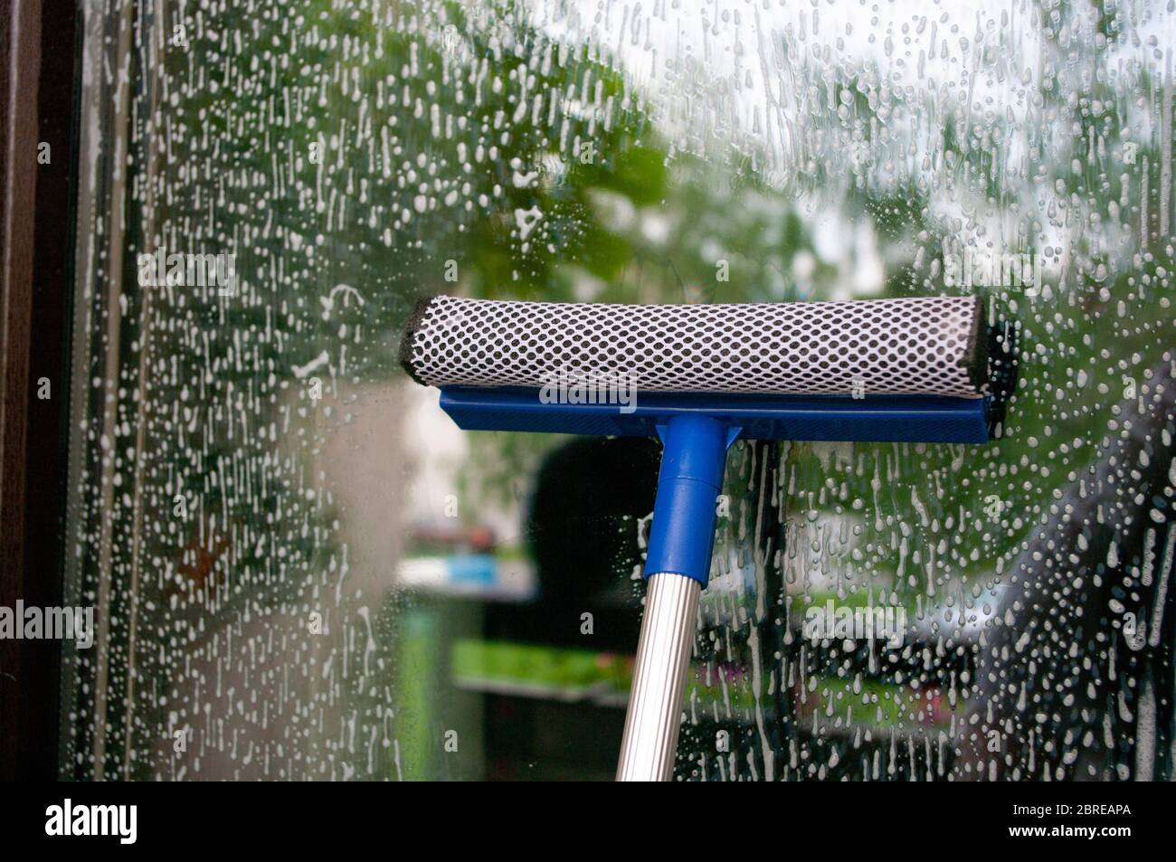 Cleaning glass of window using a squilgee Stock Photo - Alamy