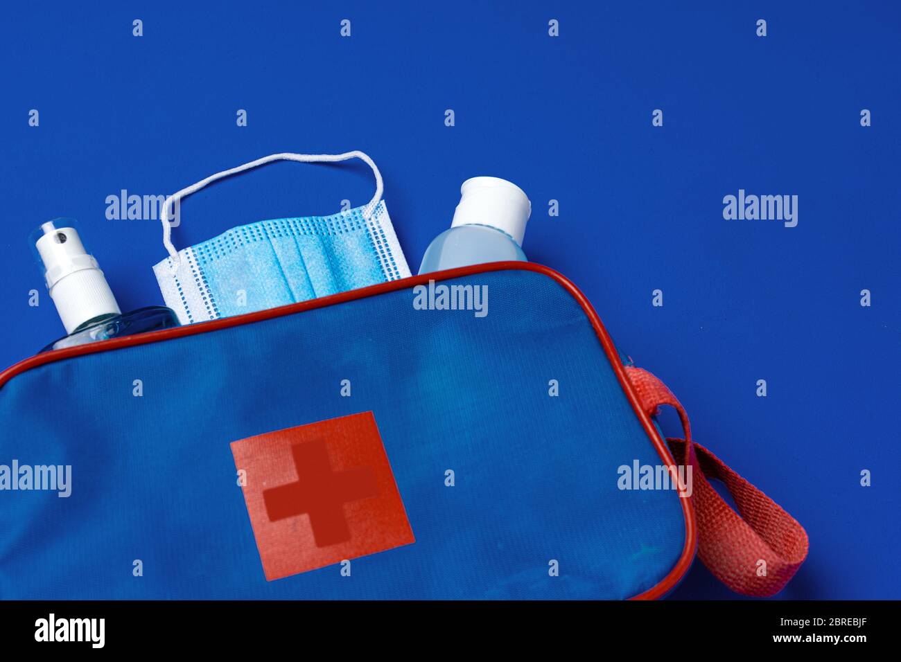 First aid kit with mask and sanitizer on blue background Stock Photo ...