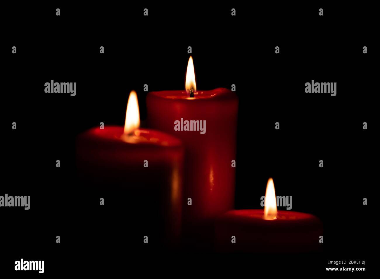 Three red candles light the darkness Stock Photo - Alamy