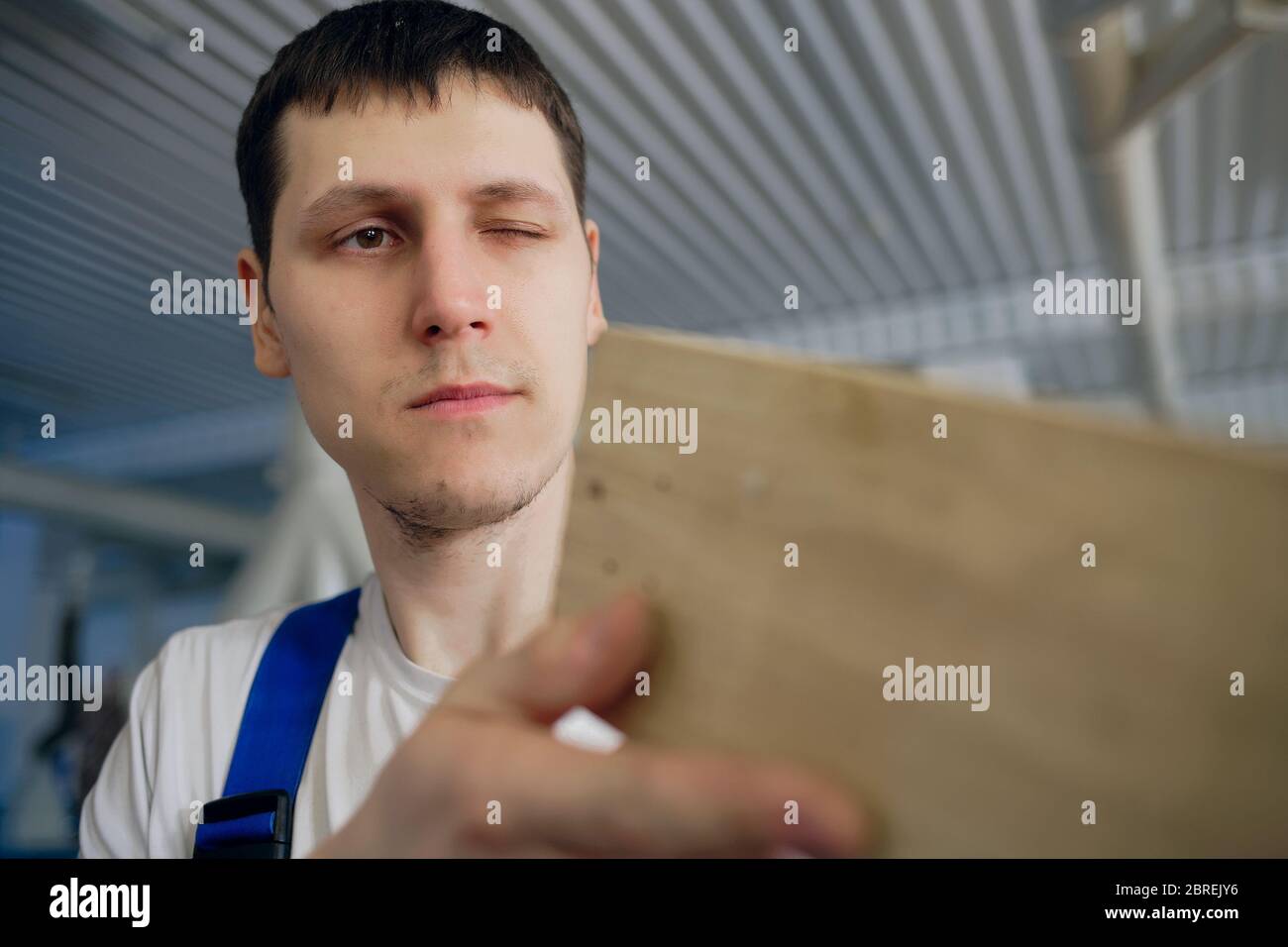 A young carpenter chooses a wooden board. Inspection and quality ...