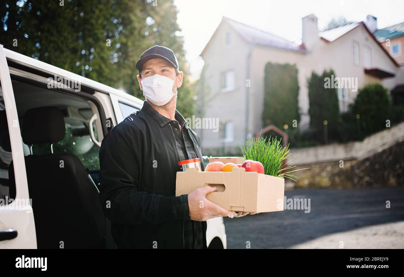 Delivery man courier with face mask delivering groceries in town Stock ...