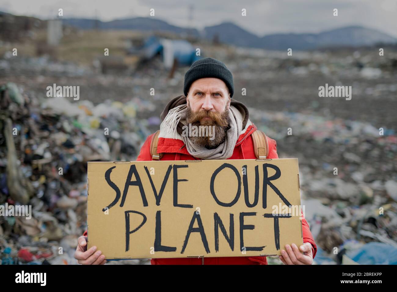 Mature man holding placard poster on landfill, environmental pollution ...