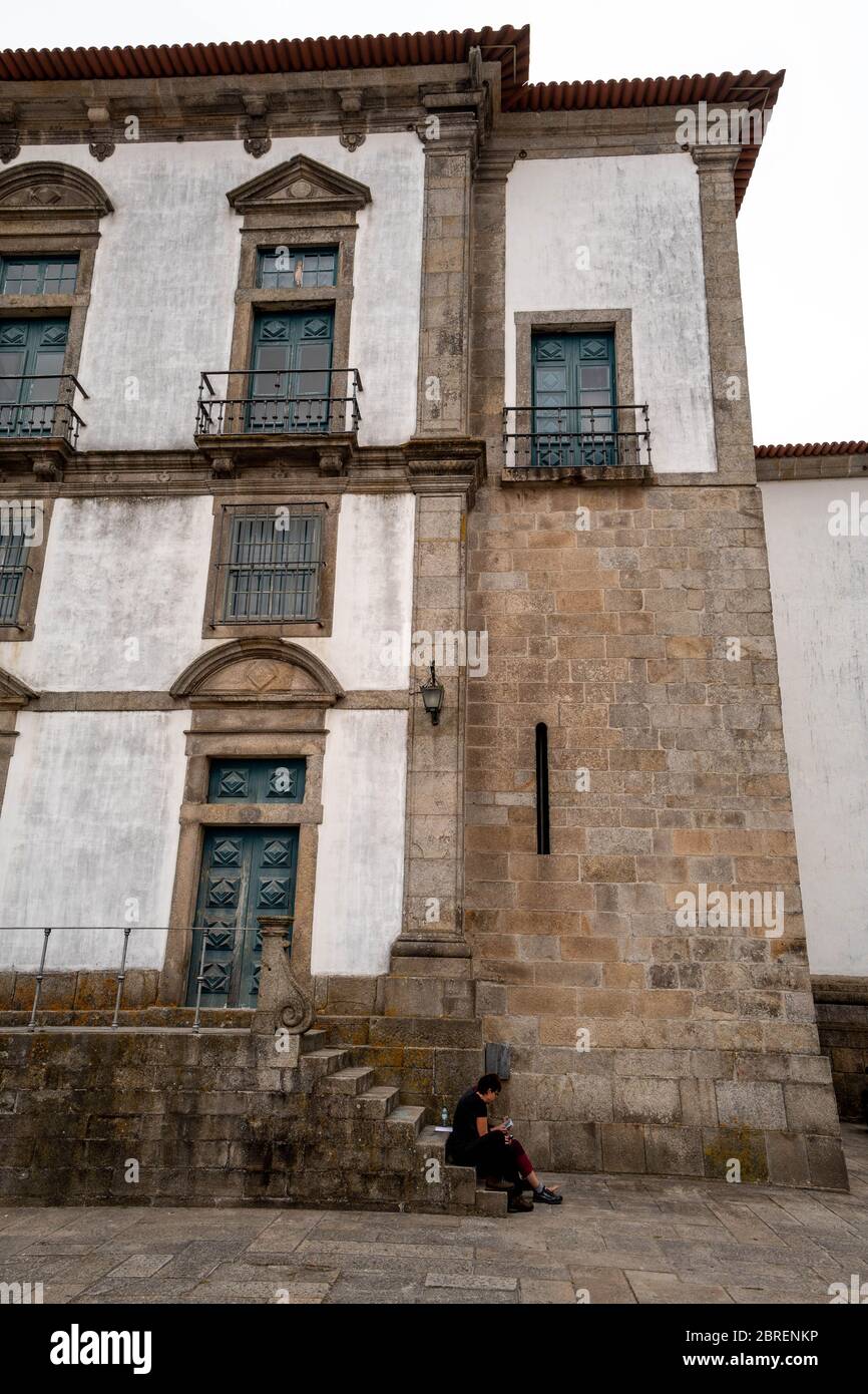 Europe, Portugal, Porto. A lady is sitting on the steps of an old house ...